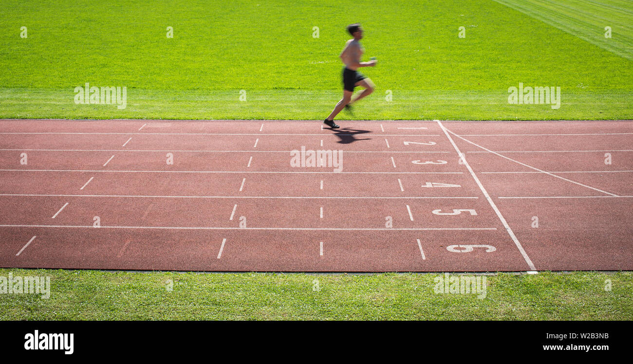 Runner on a running track finishing a race first (motion blurred image ...
