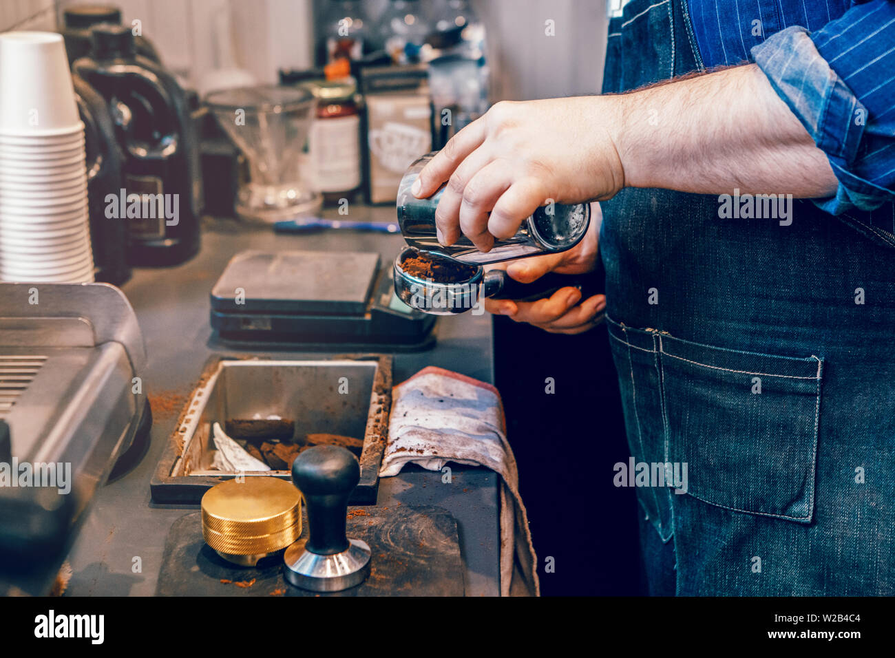Caucasian man barista filling pouring out ground black coffee into ...