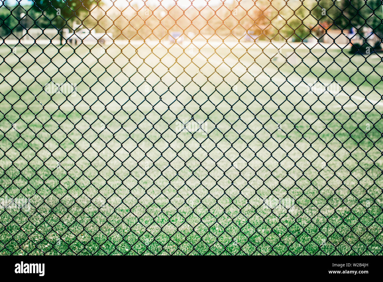 Closeup of black metal netting wire mesh fence against green field ...