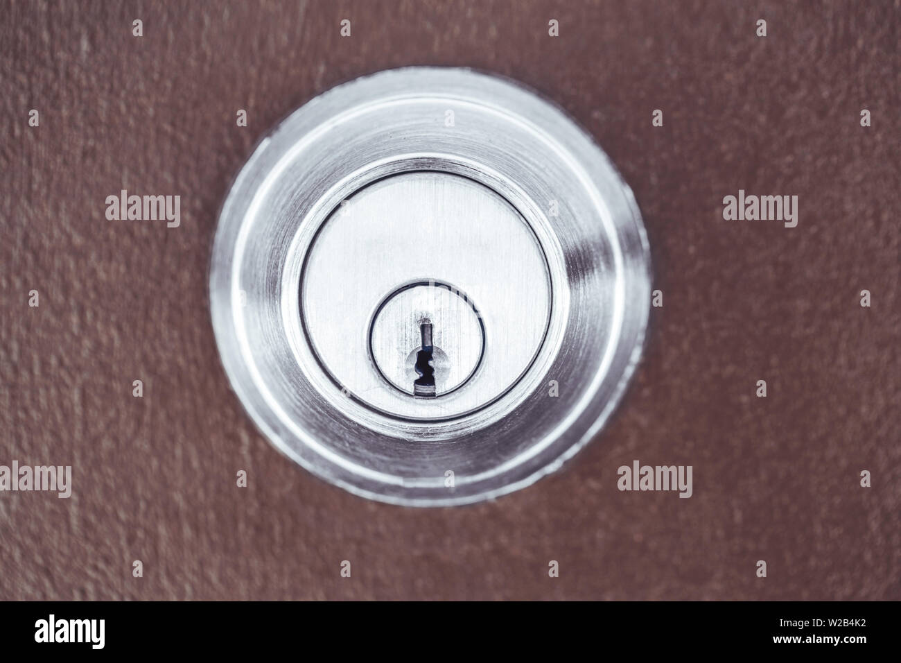 Modern new metallic grey shiny keyhole on door background. Front view ...