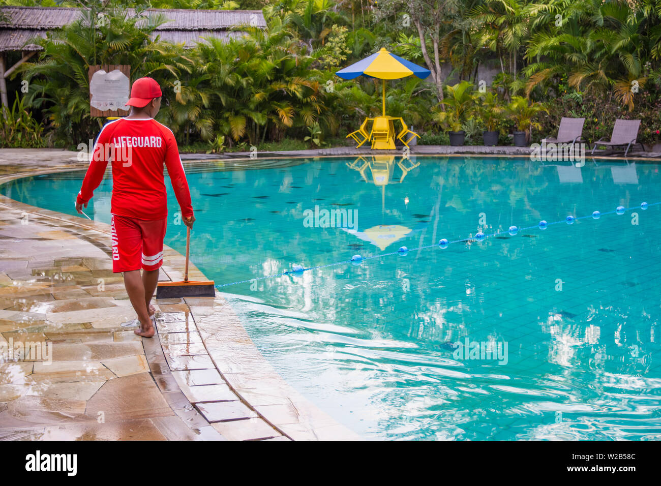 Life guard wearing red uniform working/walking around poolside keeping ...