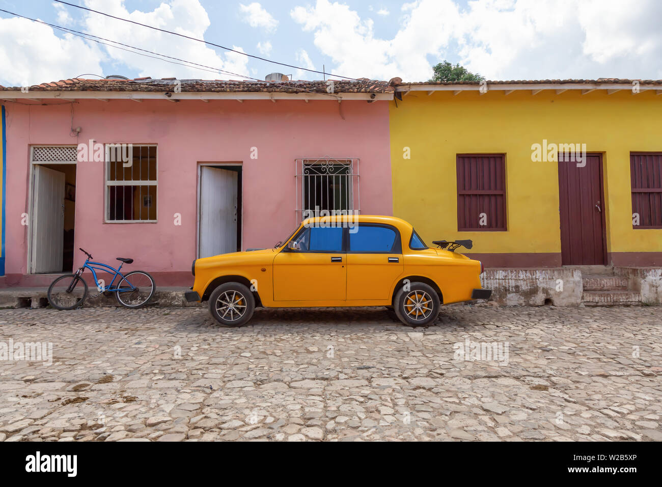 Old Yellow Car with colorful buildings in the background in a small ...