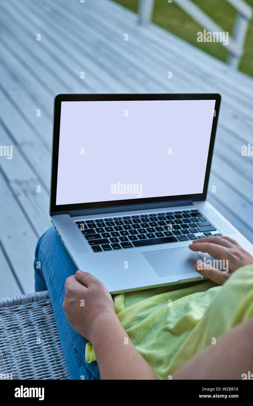 woman with laptop on deck with a swing in a rural area. The woman is ...