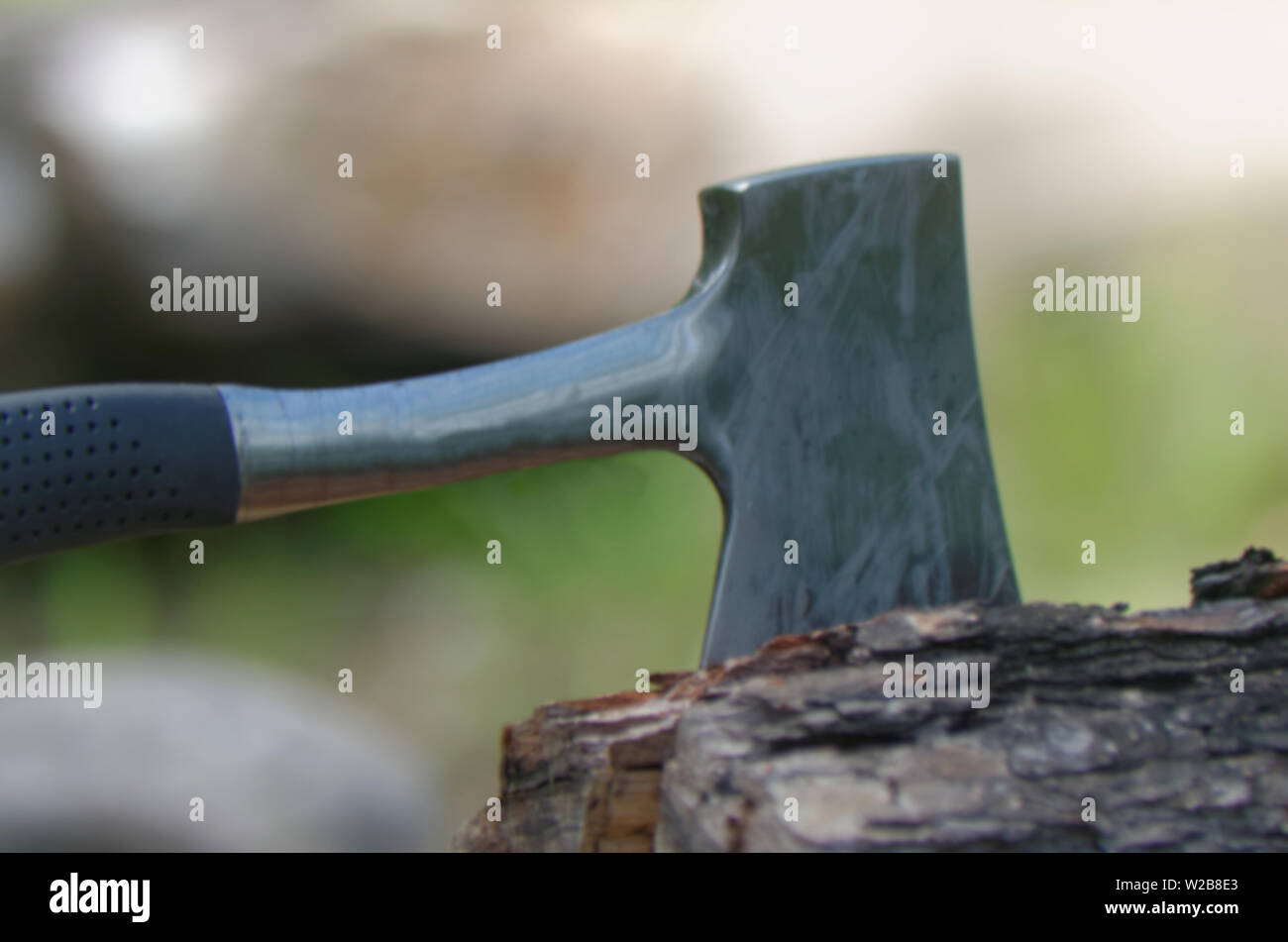 A hatchet with blade buried in a log after being used to chop fire wood ...
