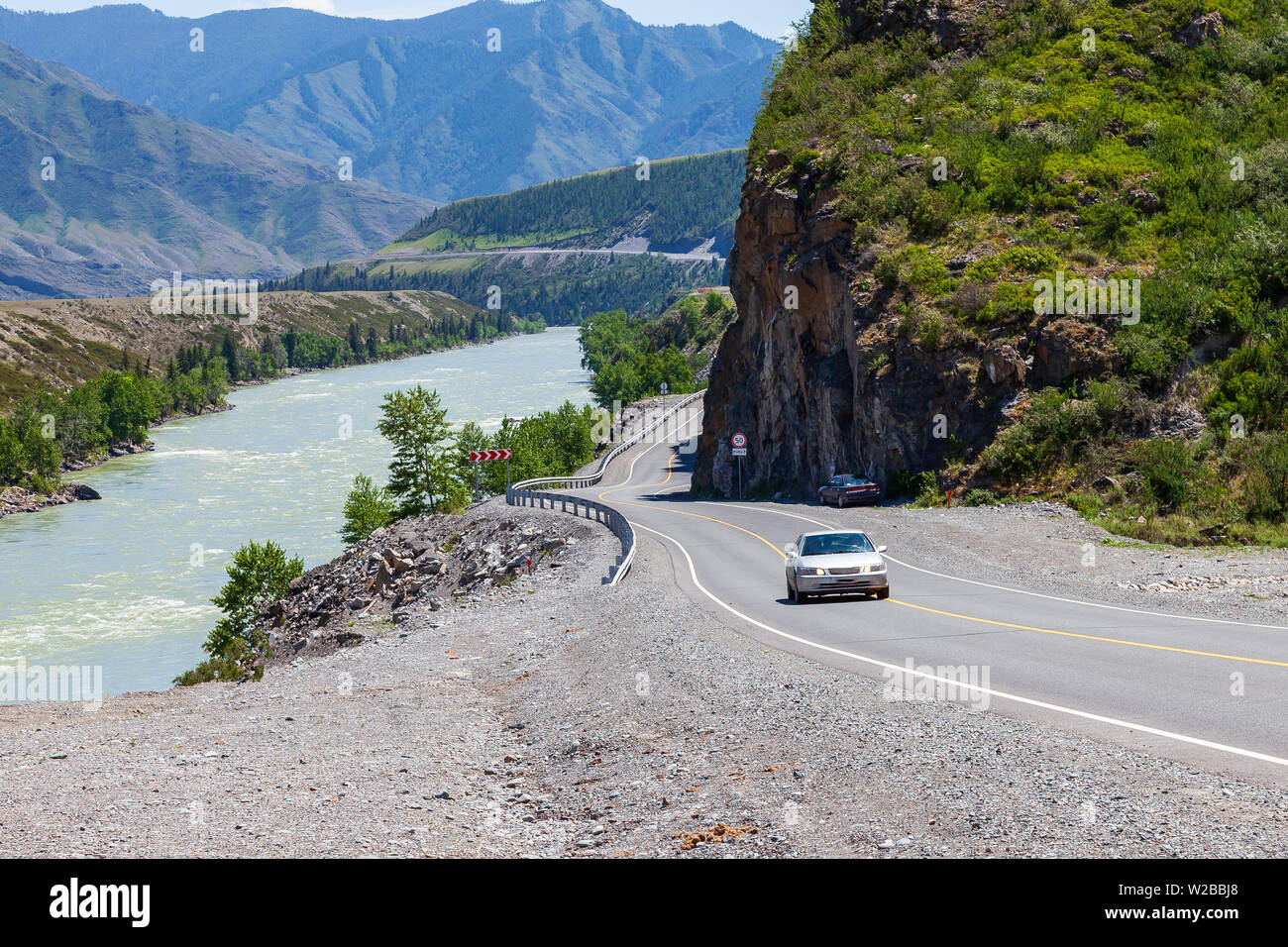 A new winding asphalt black road with a yellow dividing strip between ...