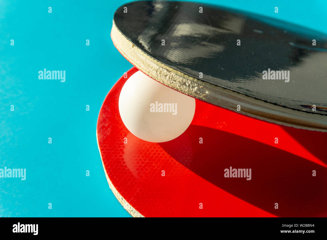 A close up of table tennis bats and ball on a blue background with copy ...