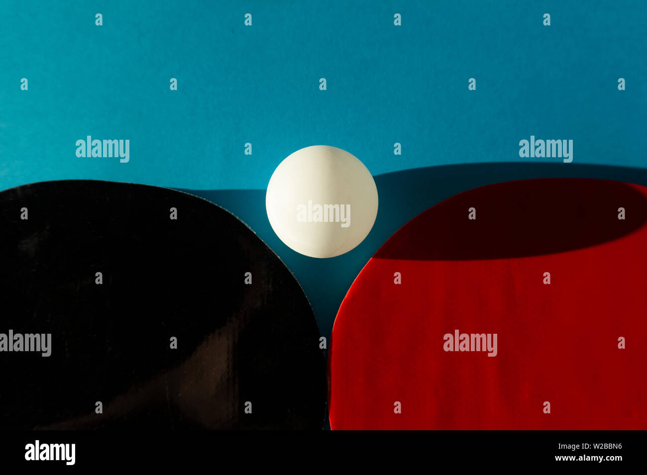 A close up of table tennis bats and ball on a blue background with copy ...