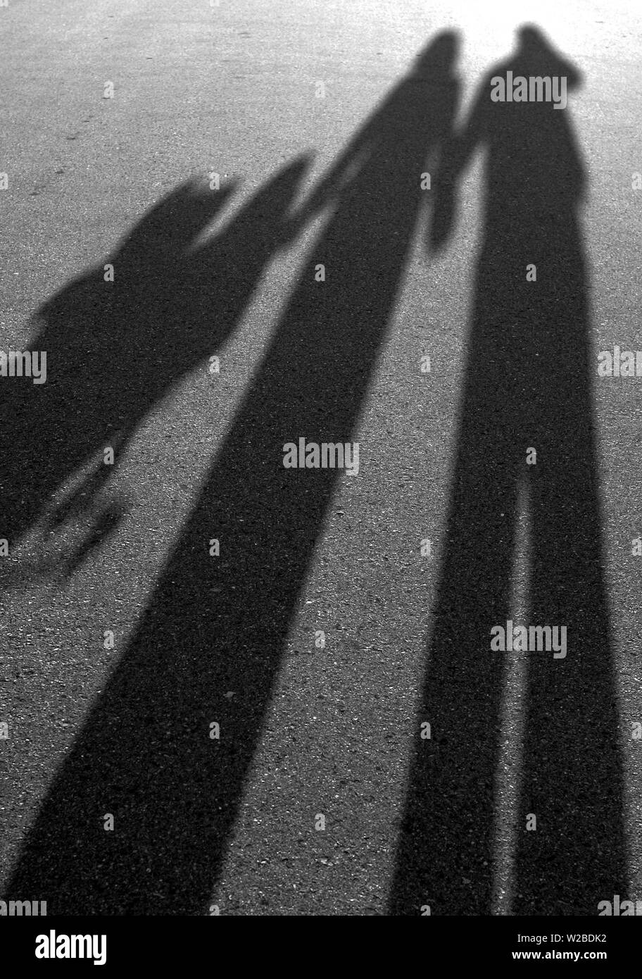 A couples shadow is cast on the road along with the baby stroller that ...