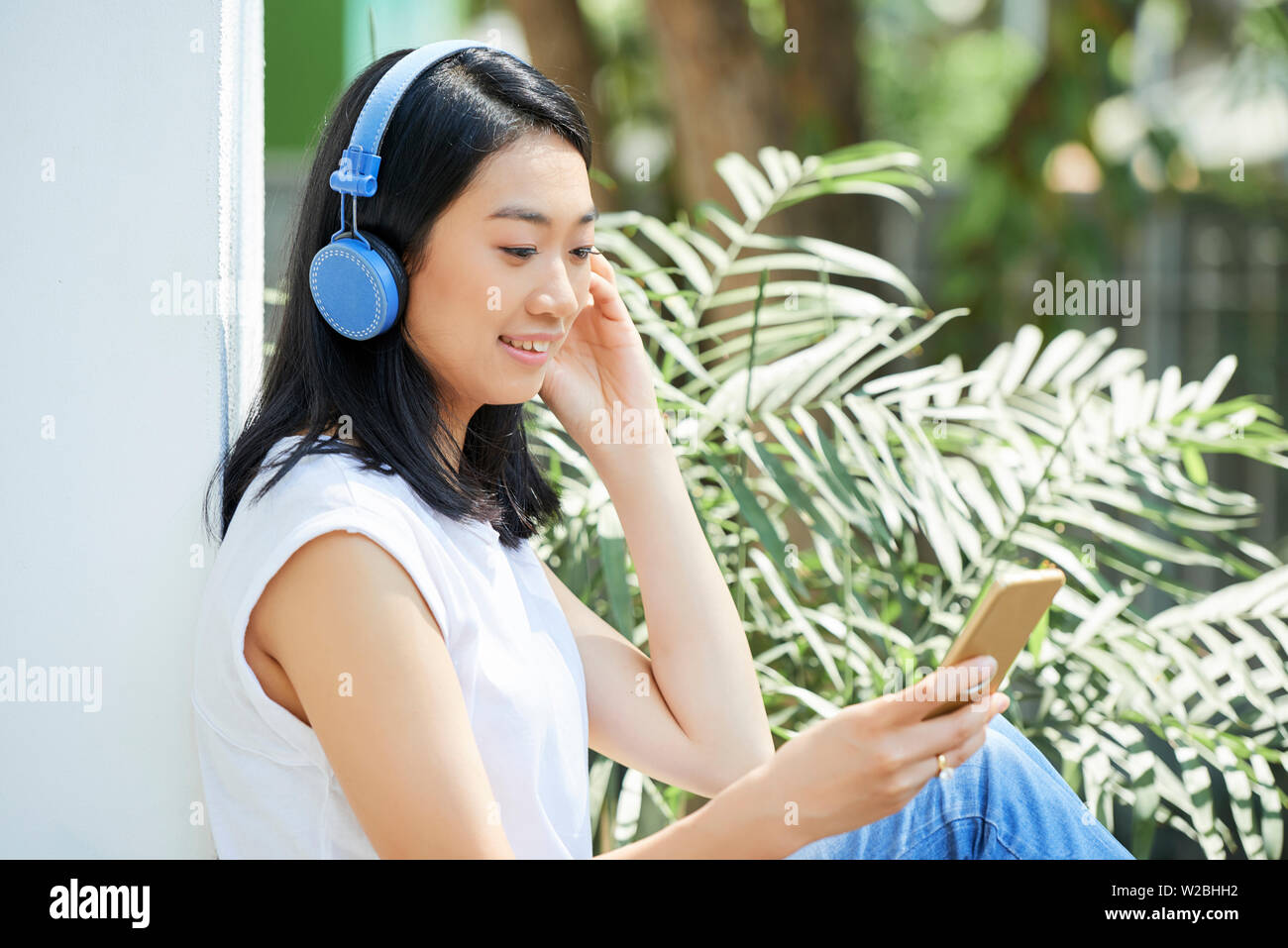 Pretty Vietnamese teenage girl listening to music in headphones and ...