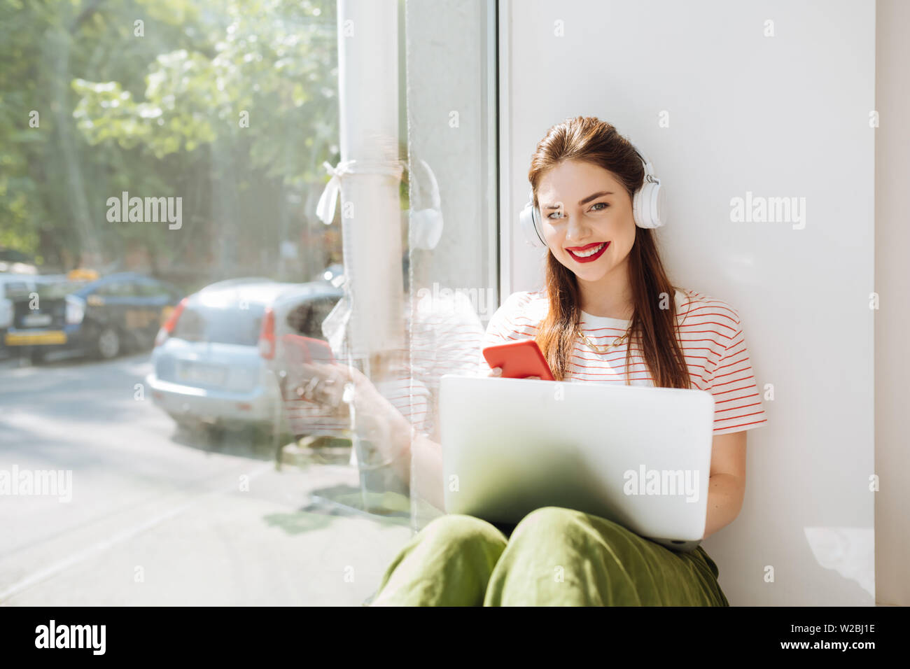 Sincere emotions. Cute student keeping smile on her face while sitting ...