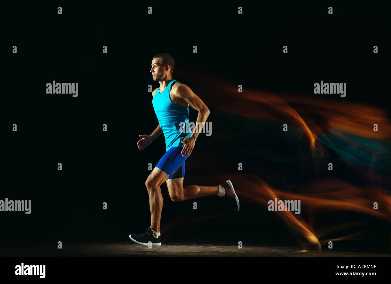 Professional male runner training isolated on black studio background ...