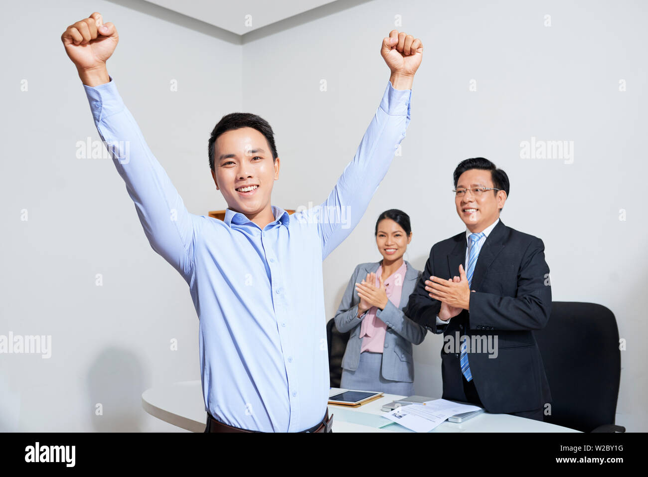 Excited happy young Asian businessman raising arms and celebrating ...