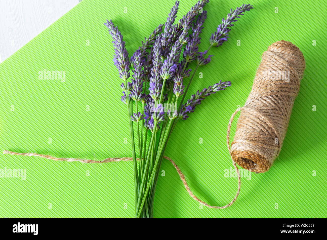 Lavender in a bunch with garden string on a green mat. White wood ...