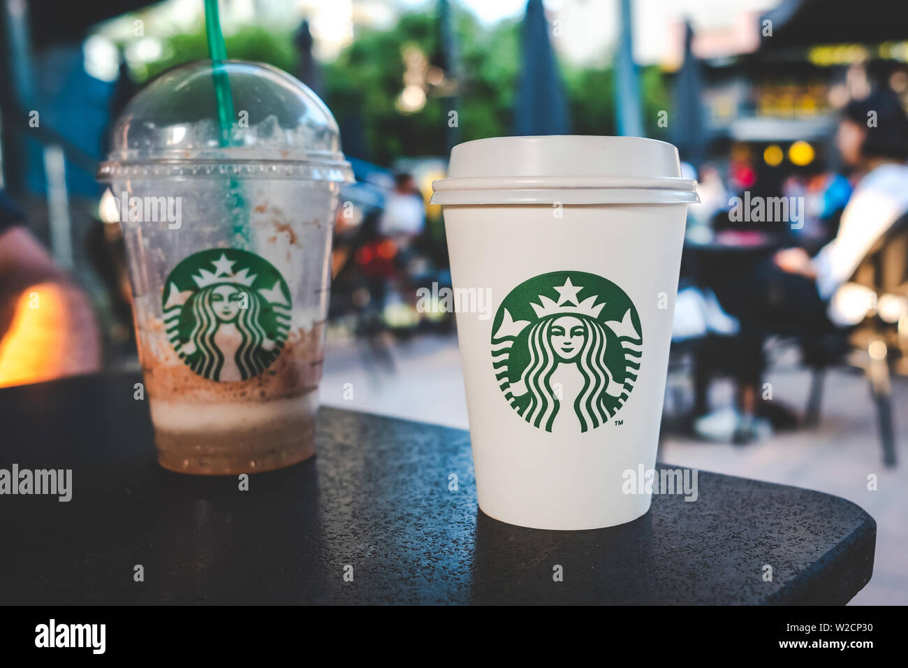 Starbucks beverage and coffee cup on the table with people in the ...