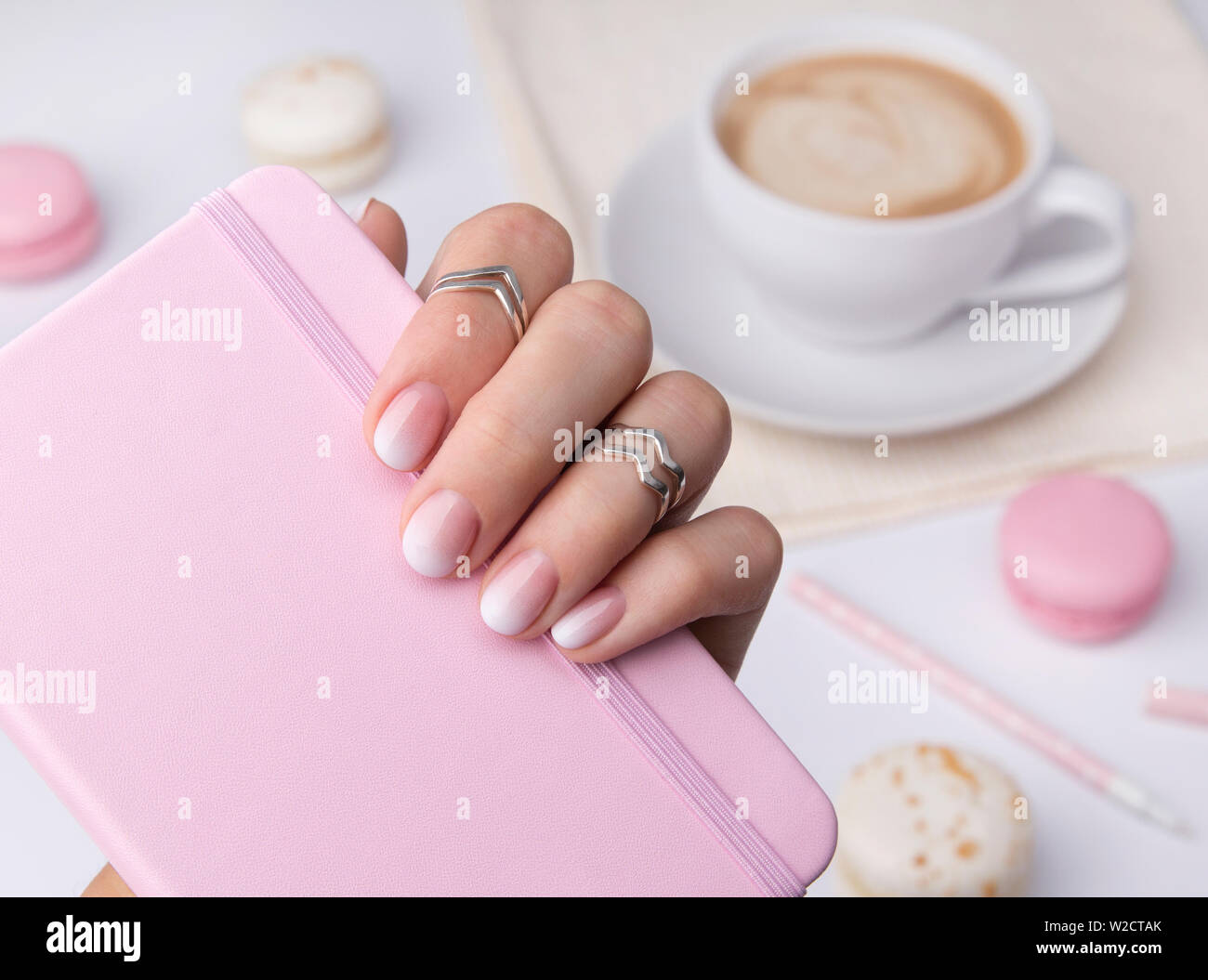 Beautiful manicured hand holding notepad at the office table. Ombre ...