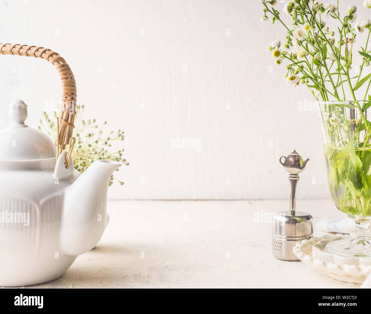 Tea concept background with teapot and tea strainer on white table ...