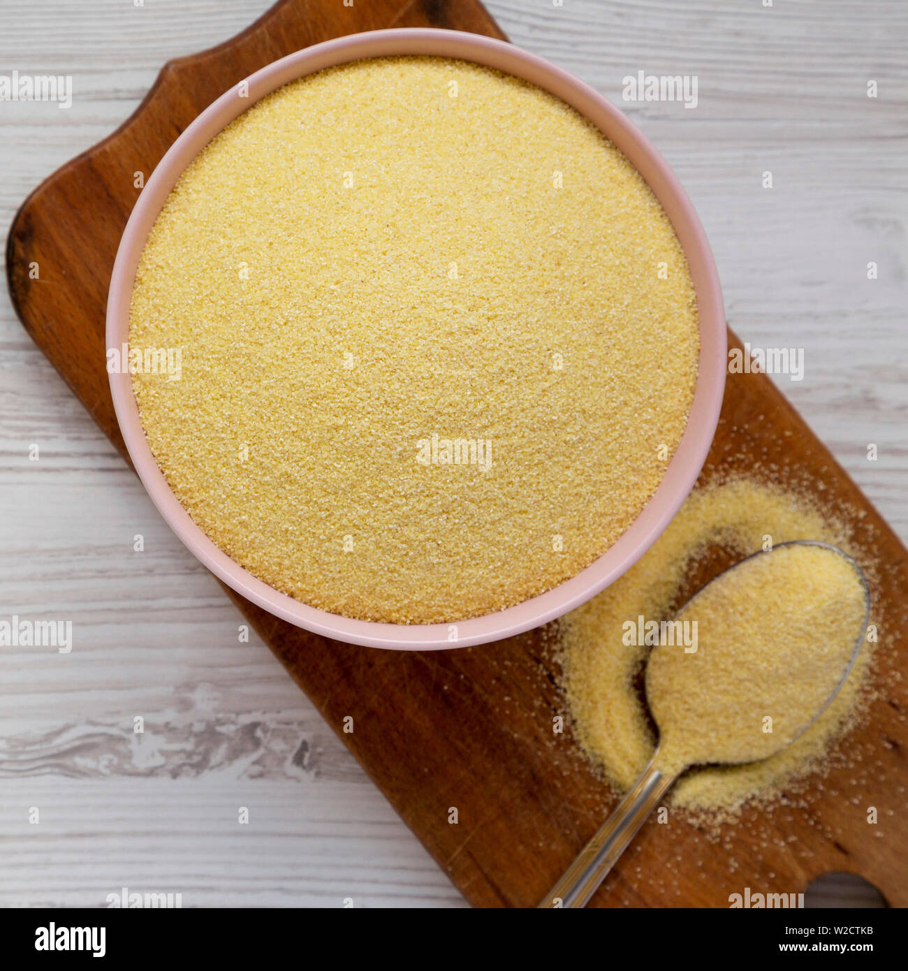 Dry semolina durum flour in a pink bowl over white wooden surface, top ...