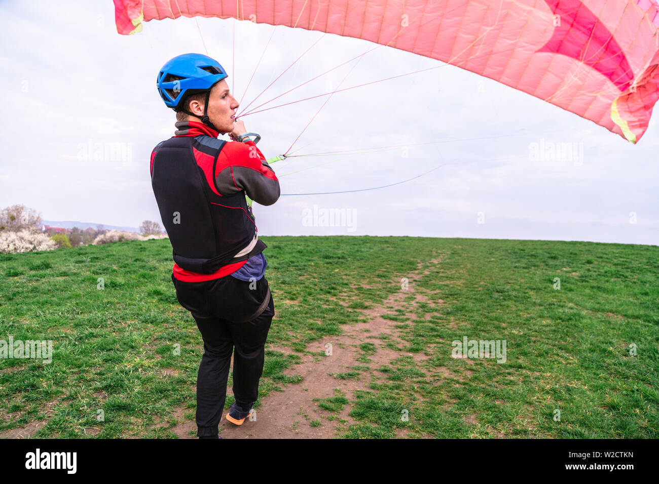 Skydiver pulls parachute behined him after landing Stock Photo - Alamy