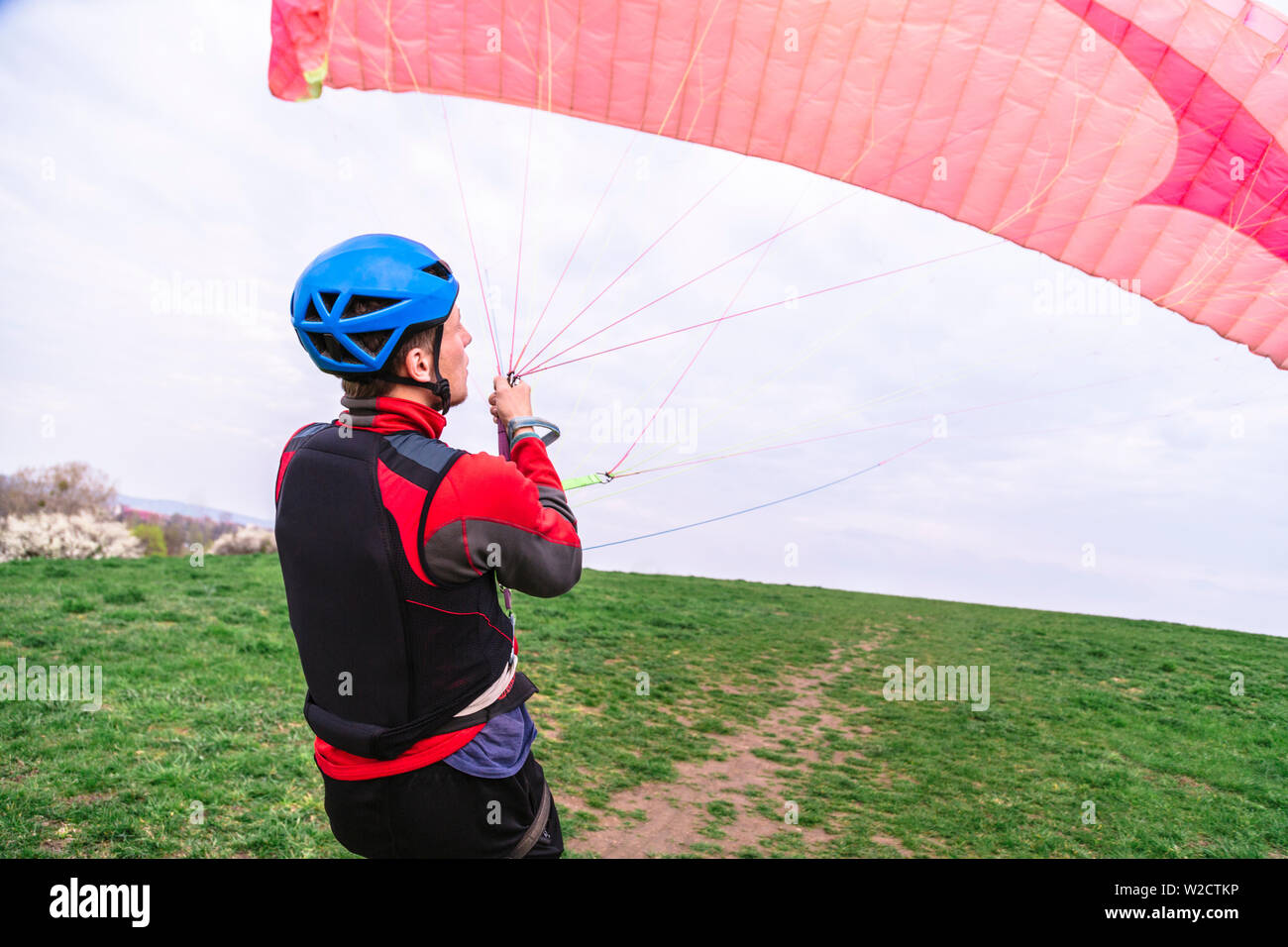 Skydiver pulls parachute behined him after landing Stock Photo - Alamy