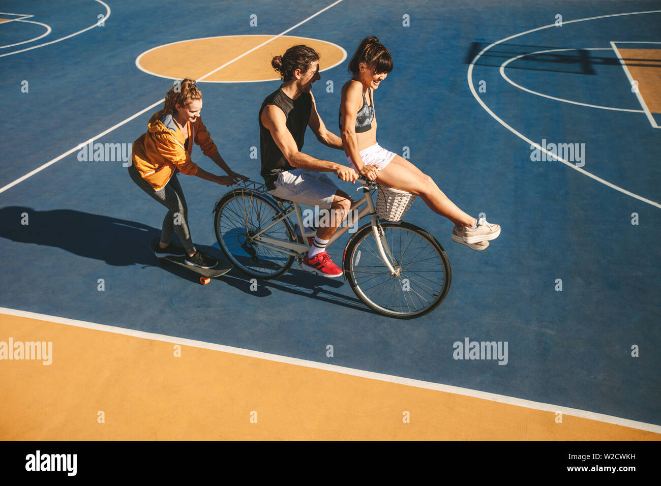 Group of friends having fun riding a bicycle and skateboard on ...