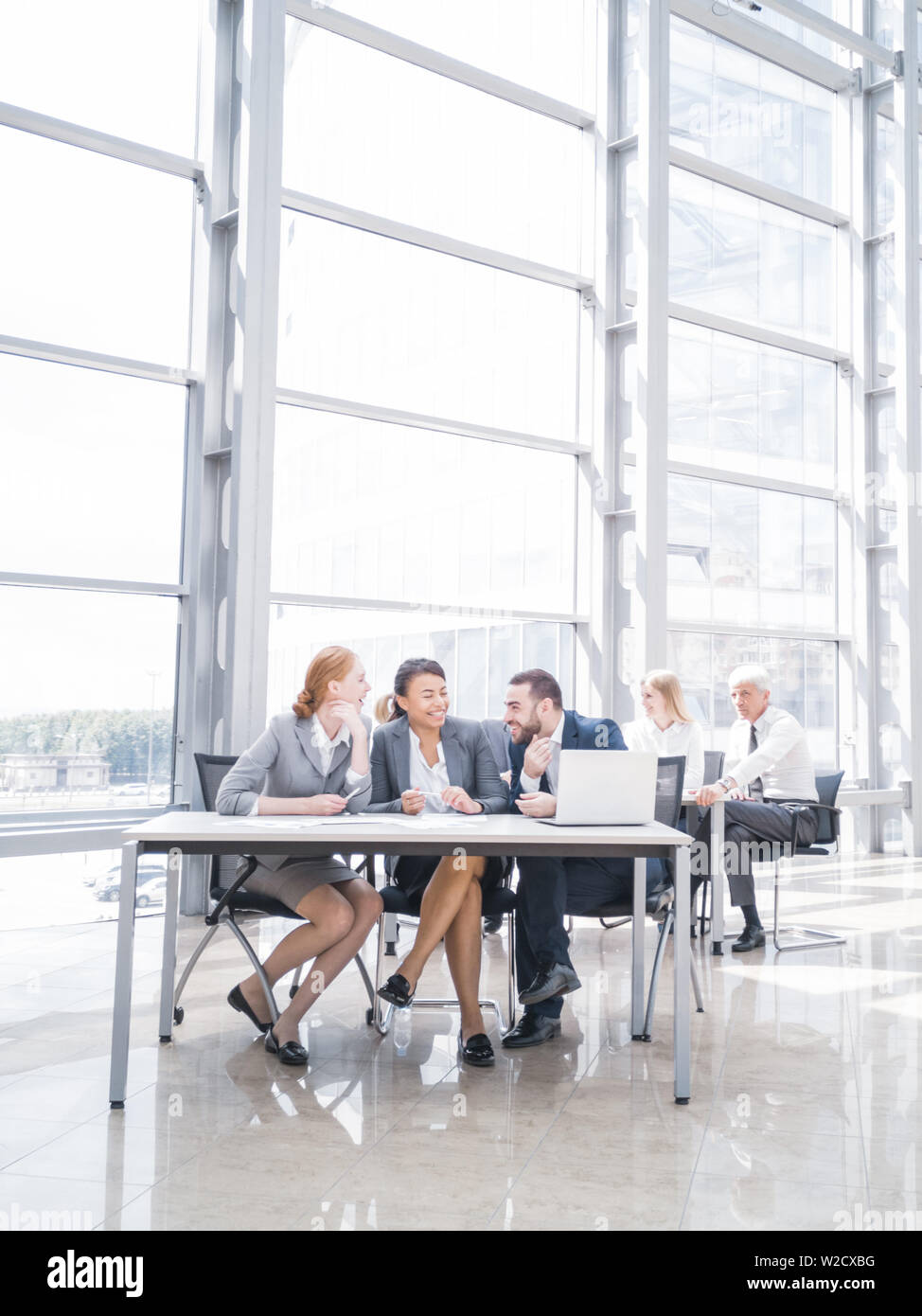 Business people laughing at workplace sitting at conference table with ...