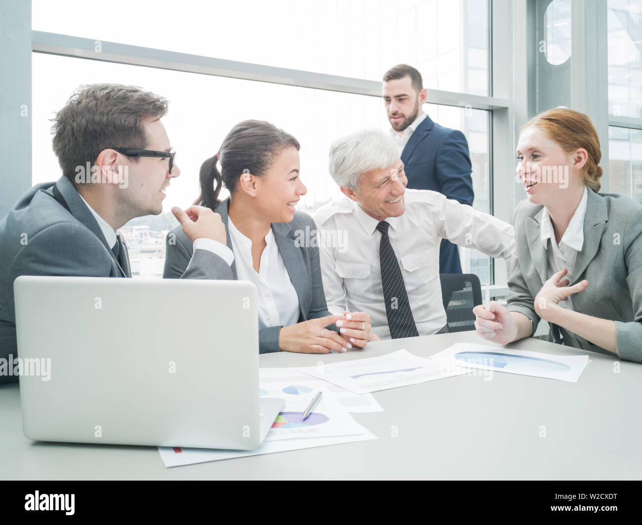 Business team sitting by the table with laptop and documents in office ...