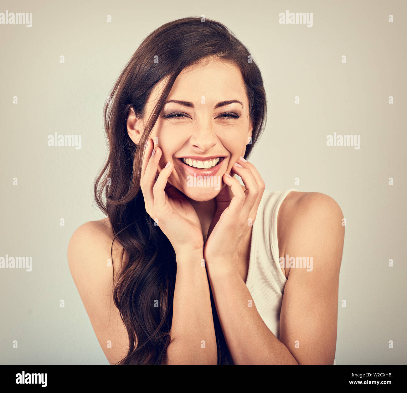 Beautiful natural toothy laughing woman with closed eyes holding the ...