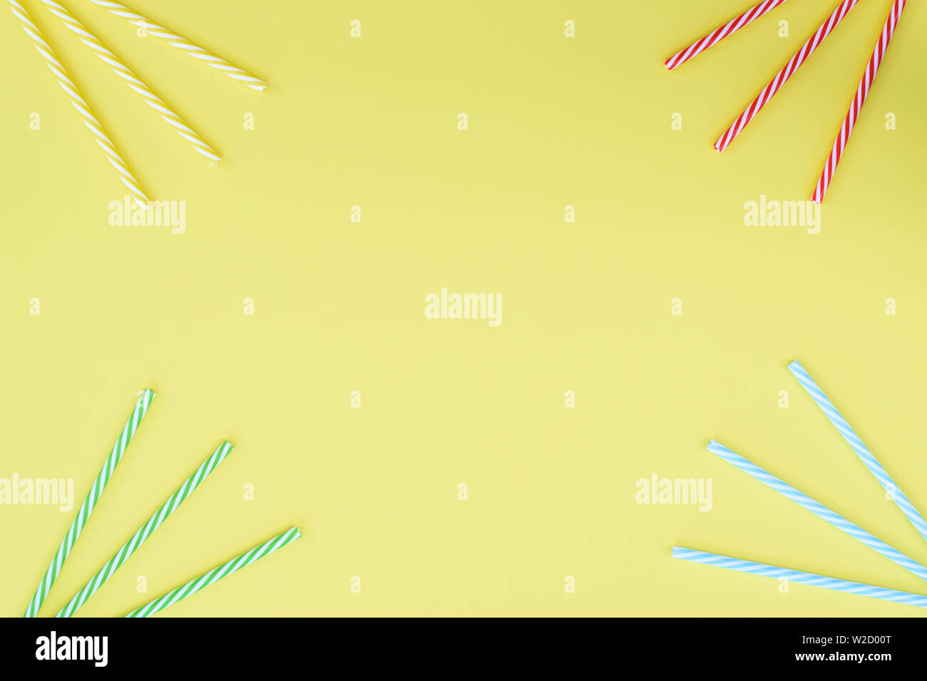 Multi-colored cocktail straw plastic tubes on a bright yellow ...