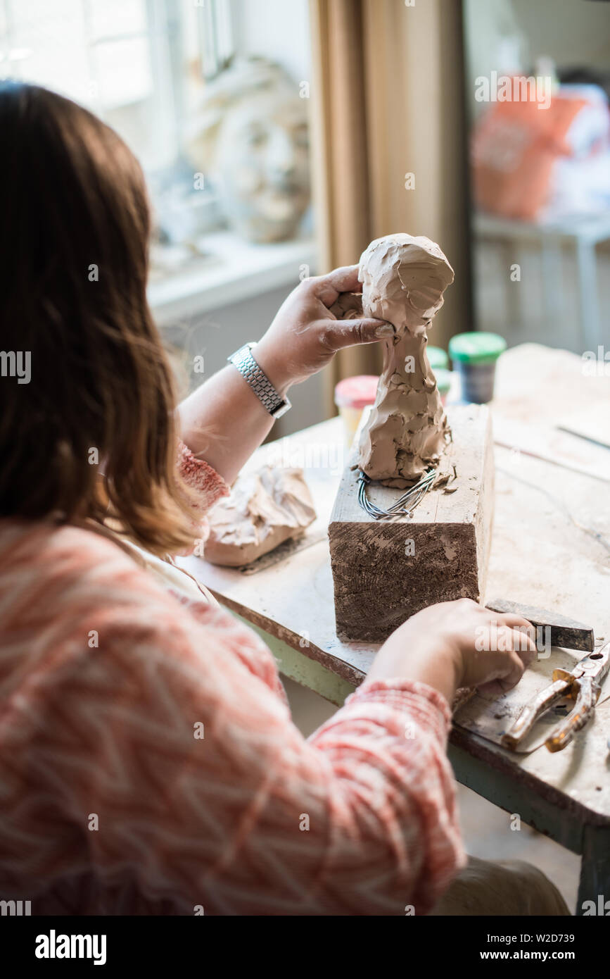 Lady sculptor working in her studio, ceramis artist's hands making ...