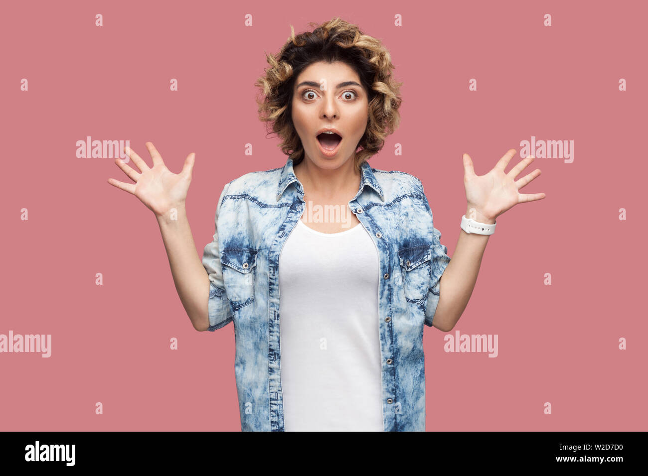 Portrait of surprised young woman with curly hairstyle in casual blue ...