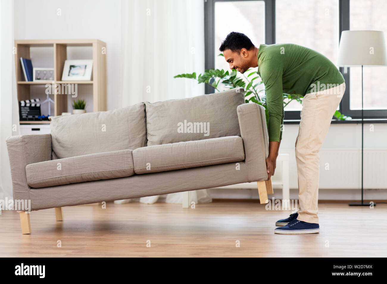 happy indian man moving sofa at home Stock Photo - Alamy