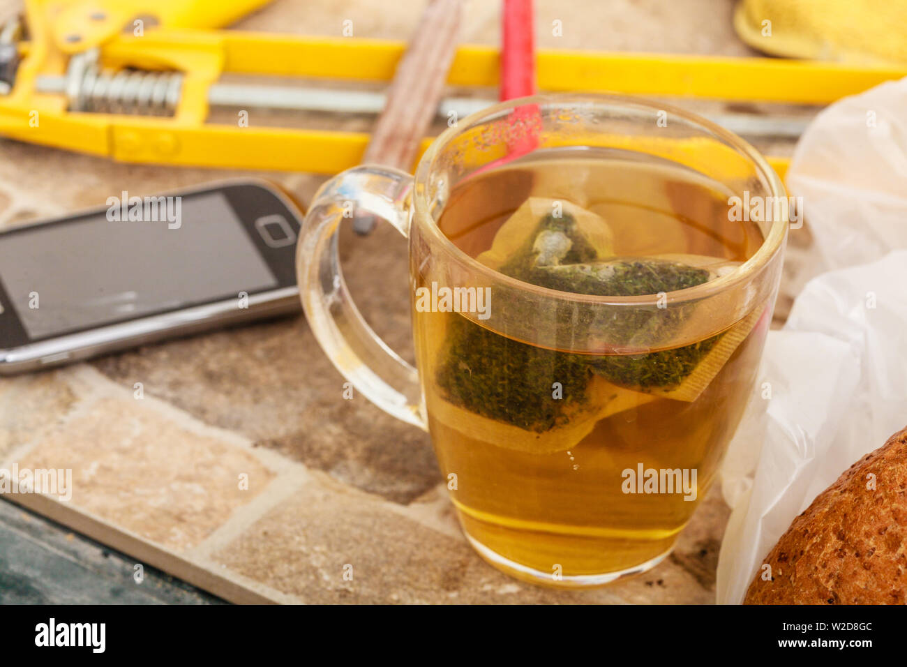 Break at work, cup of tea and smartphone in messy interior after room ...