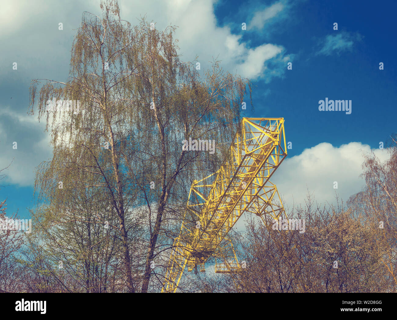 Yellow gantry crane behind the trees on the territory of the enterprise ...