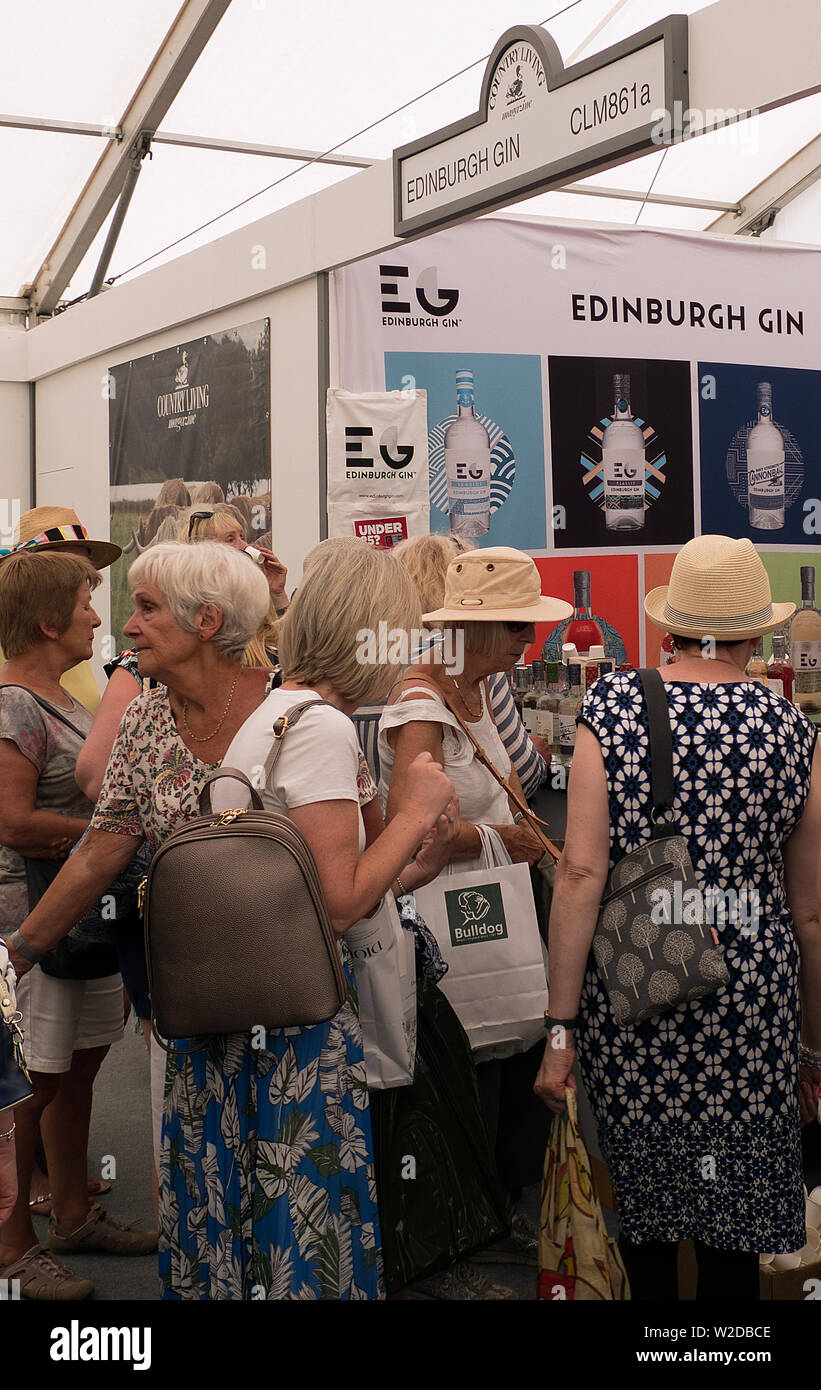 Women huddle around a Gin stand at the Hampton Court Palace Festival in ...
