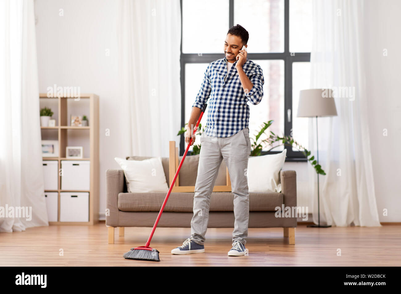 man with broom cleaning and calling on smartphone Stock Photo - Alamy