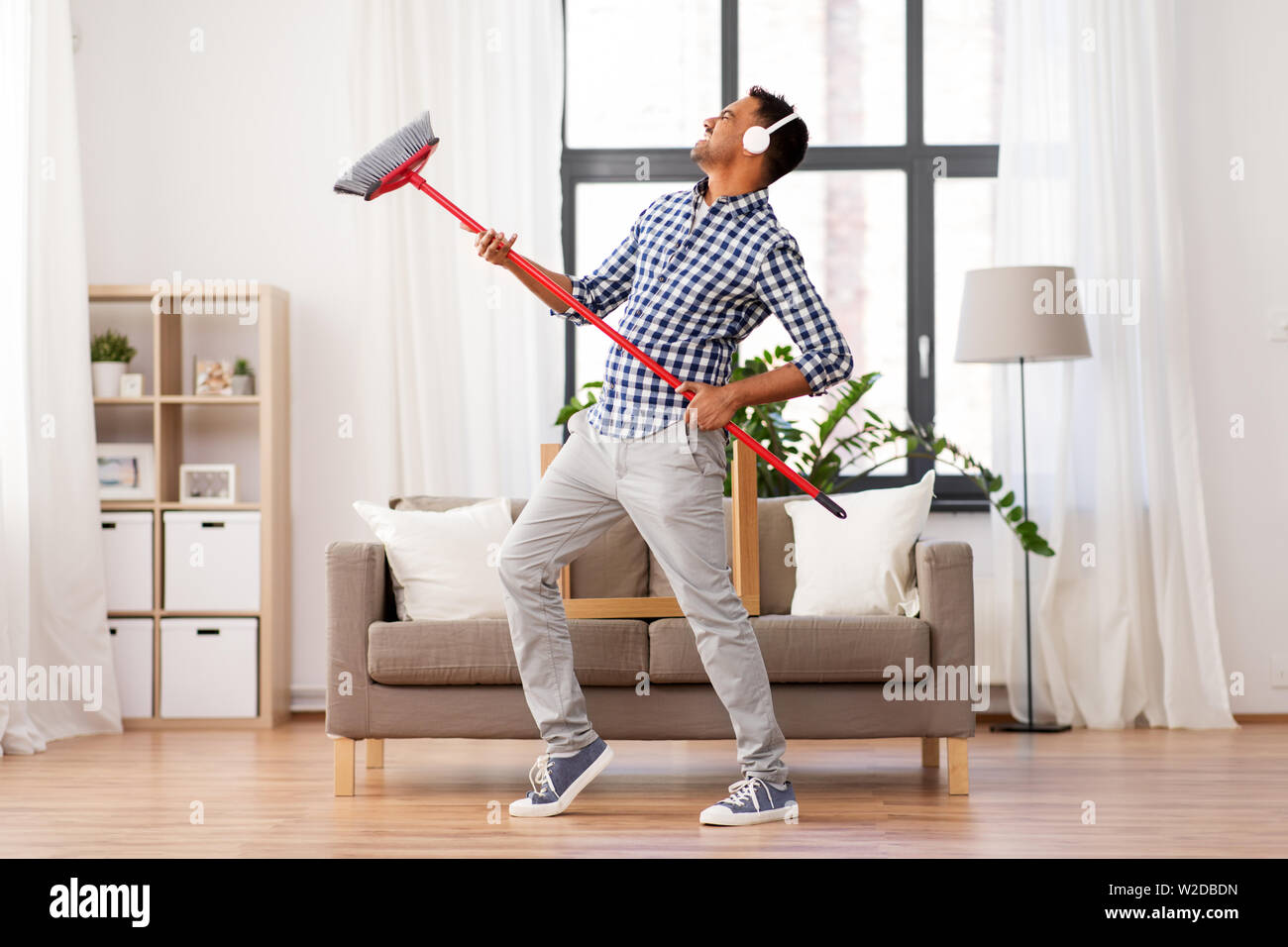 man with broom cleaning and having fun at home Stock Photo - Alamy