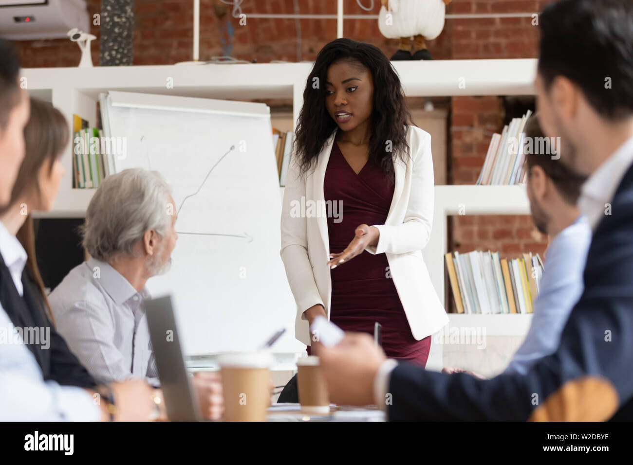 African female business coach talk to employees give flipchart ...