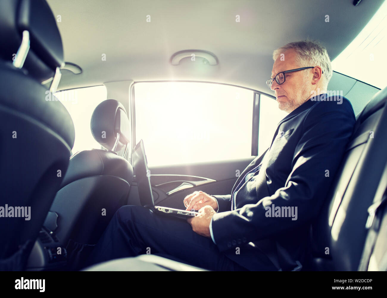 senior businessman with laptop driving in car Stock Photo - Alamy