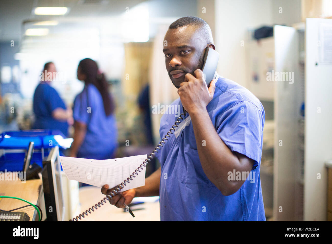 Male NHS nurse at a workstation in a Hospital ward dealing with ...