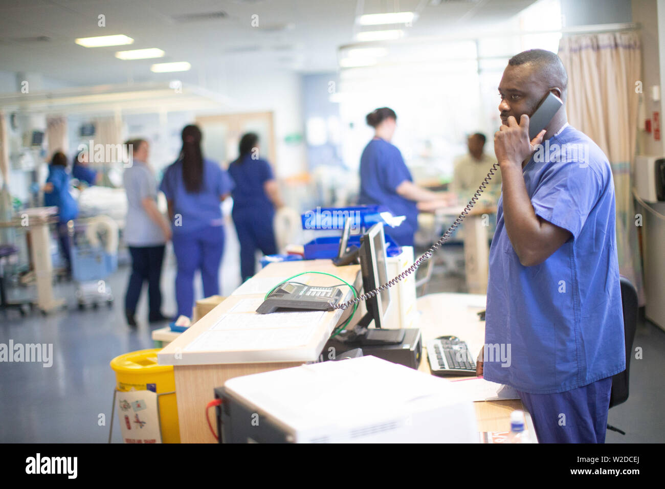 Male NHS nurse at a workstation in a Hospital ward dealing with ...
