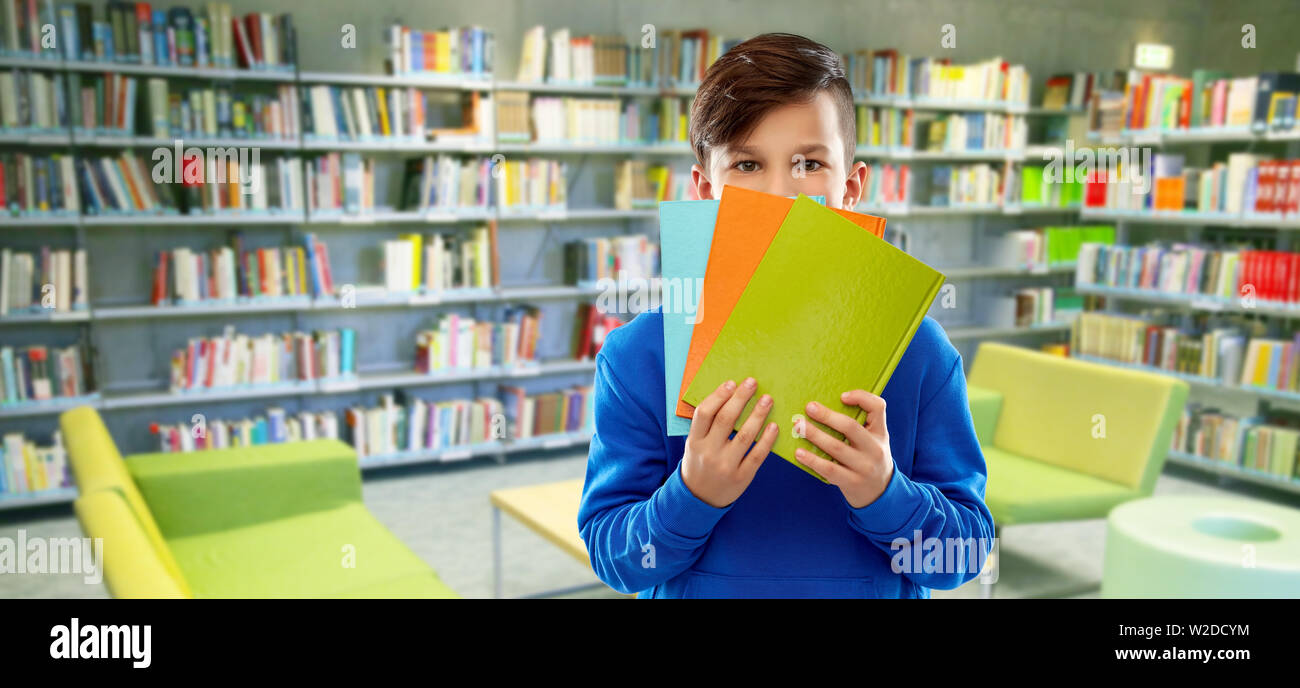 shy student boy hiding behind books at library Stock Photo - Alamy