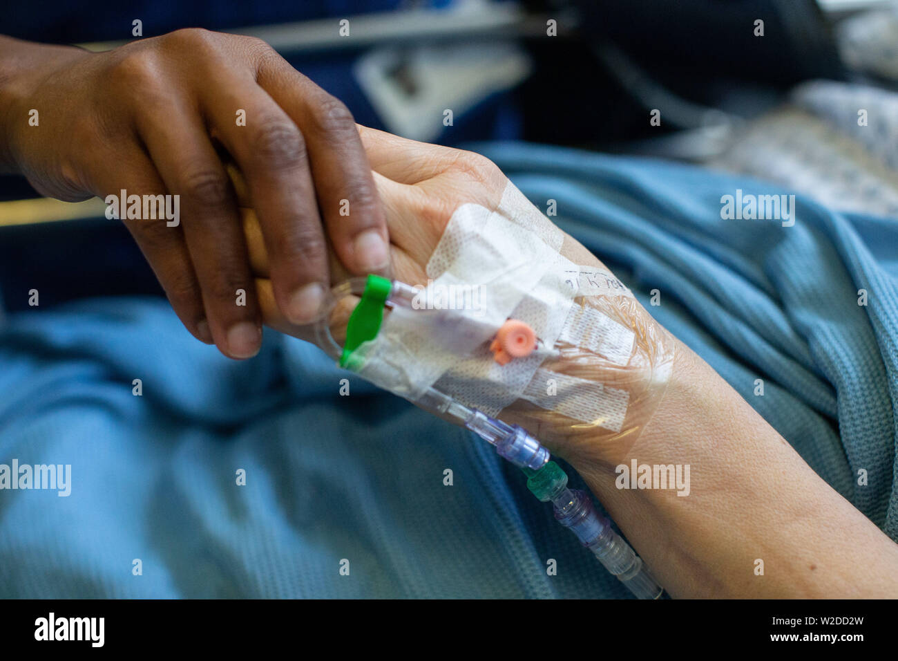 Detail of Hand of a nurse comforting a patient's hand. The patient has ...