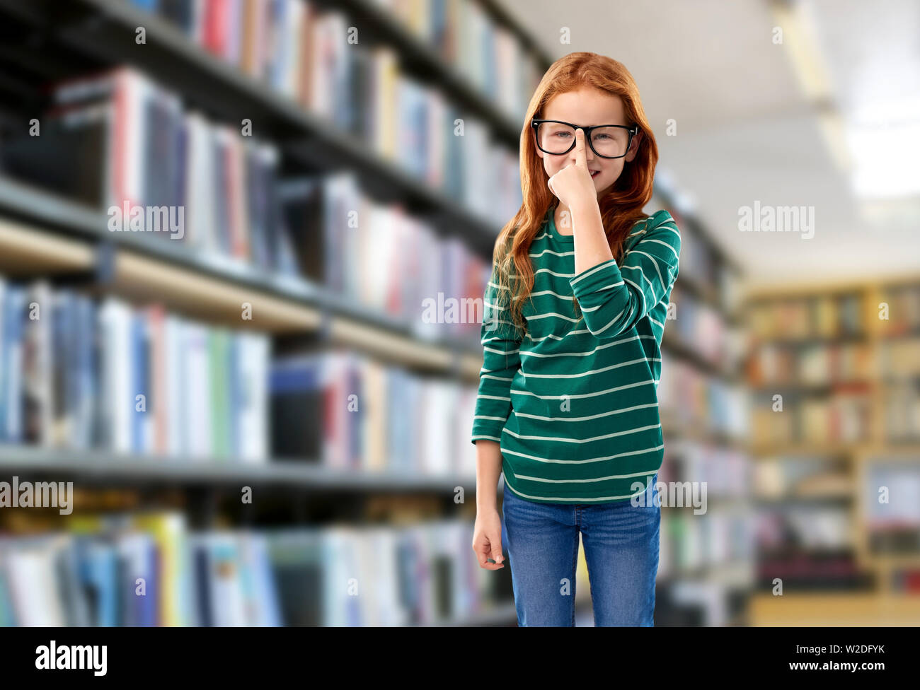 cute red haired student girl in glasses at library Stock Photo - Alamy