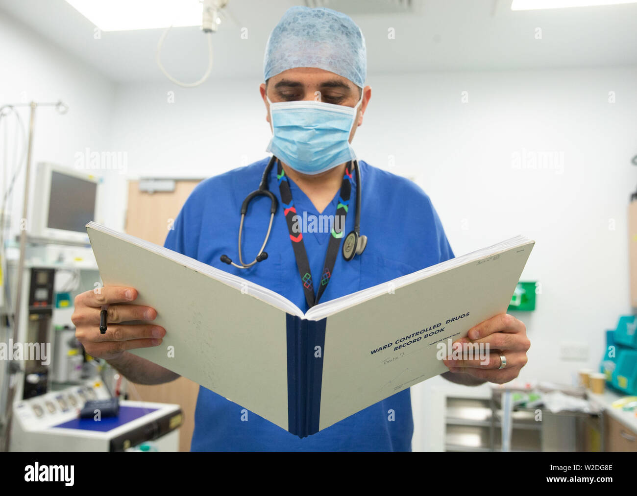 Surgeon studying patient notes and treatment in an NHS Hospital prior ...