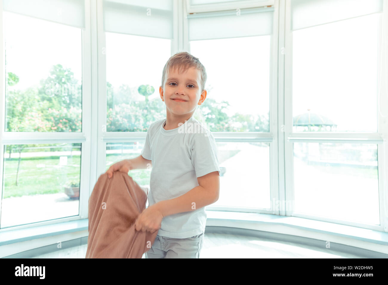 Happy cute boy standing in front of the window Stock Photo - Alamy