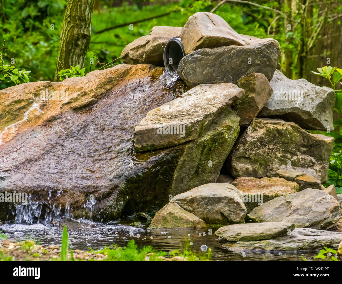 small waterfall made out of boulders in a garden, simple and beautiful ...