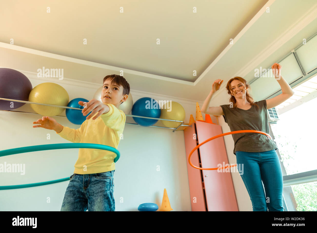Nice joyful woman showing how to rotate hula hoop Stock Photo - Alamy