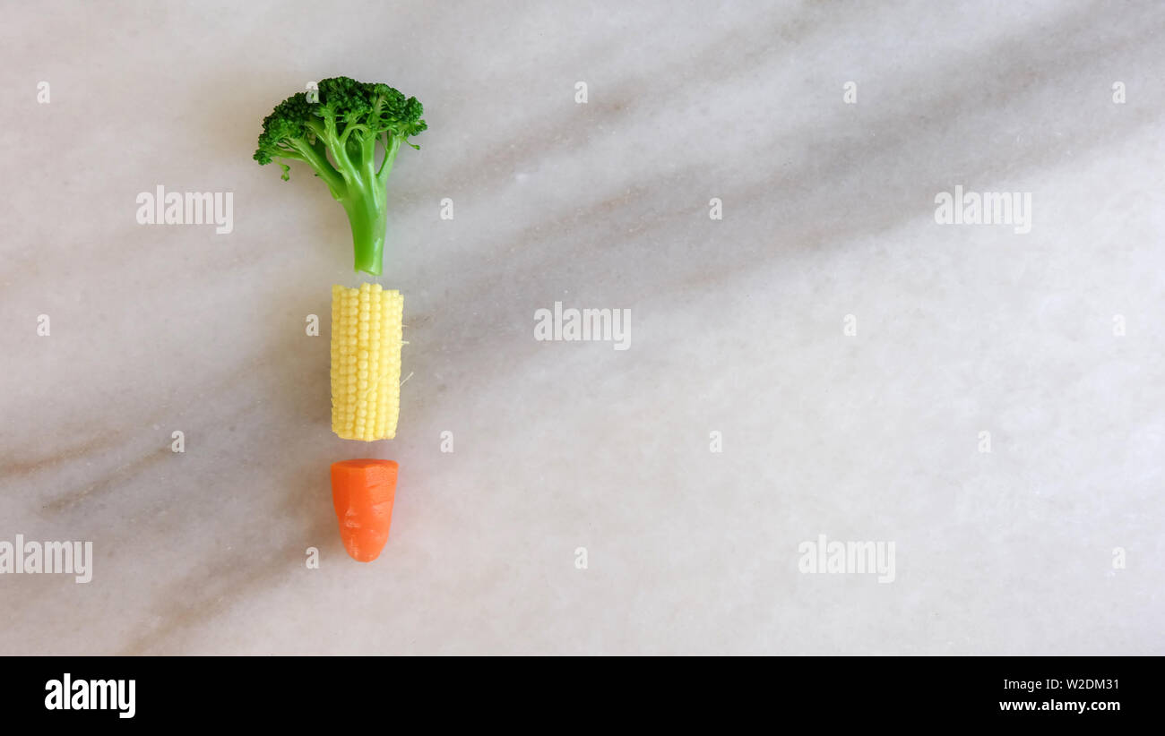 Arrangement of broccoli, baby corn and carrot, on a marble countertop ...