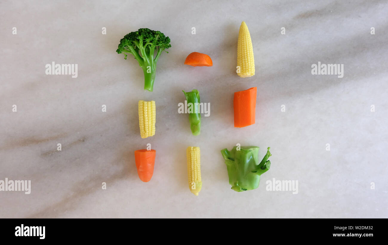 Arrangement of broccoli, baby corn and carrot, on a marble countertop ...