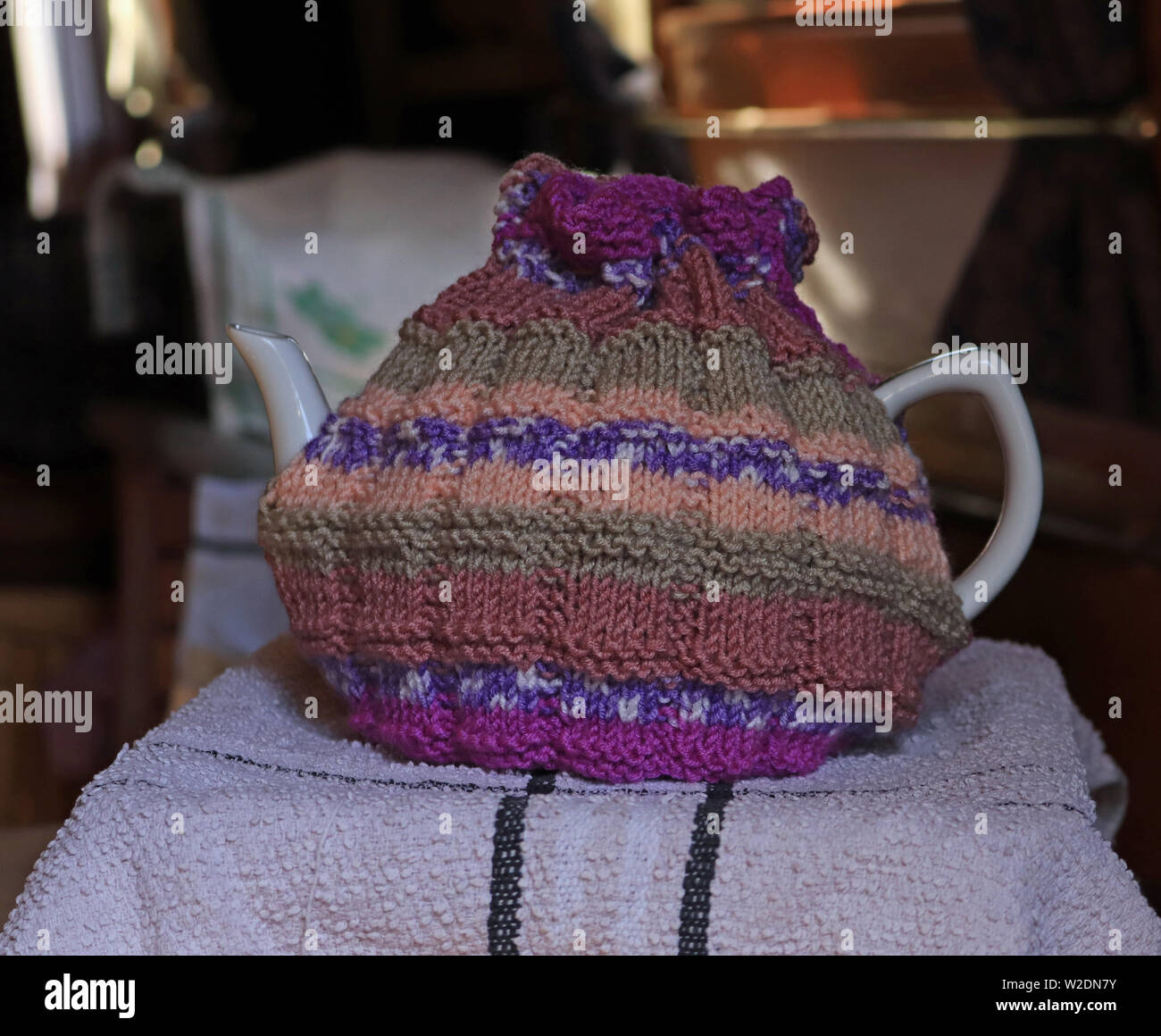 A hand knitted tea cosy in Brown, orange, green and purple shades of ...
